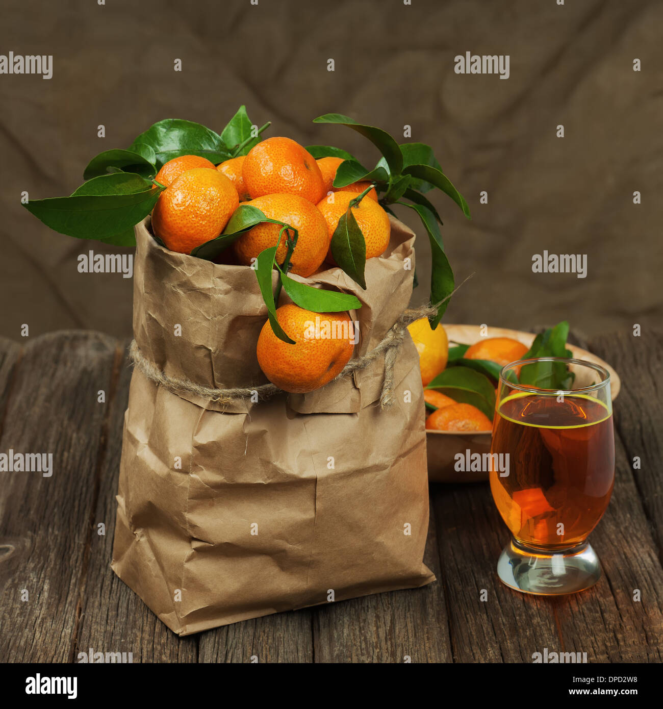 Fresh tangerines in recycle paper bag and glass of juice on wooden ...
