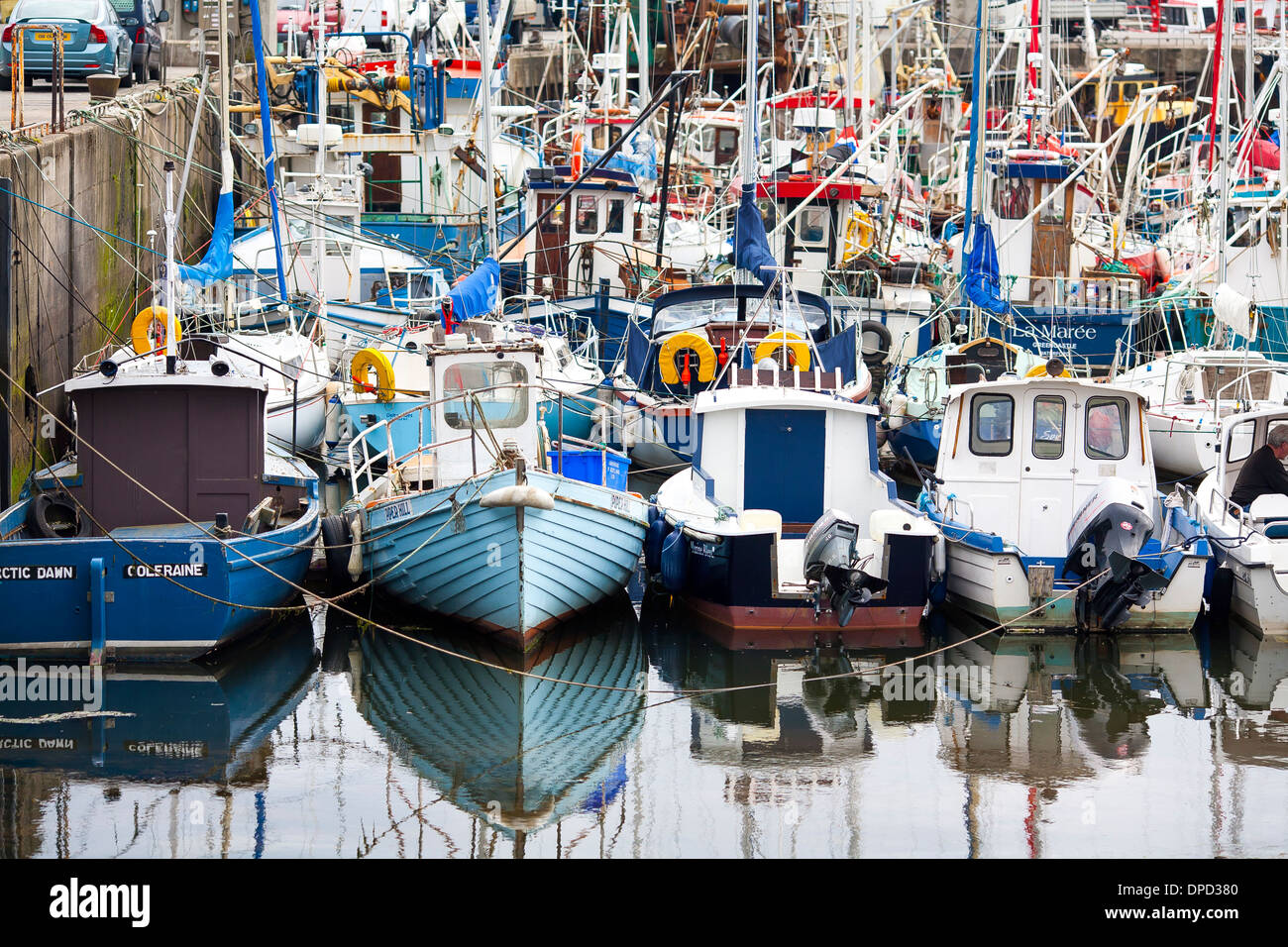 Fishing boats in a line moored and packed alongside each other in ...