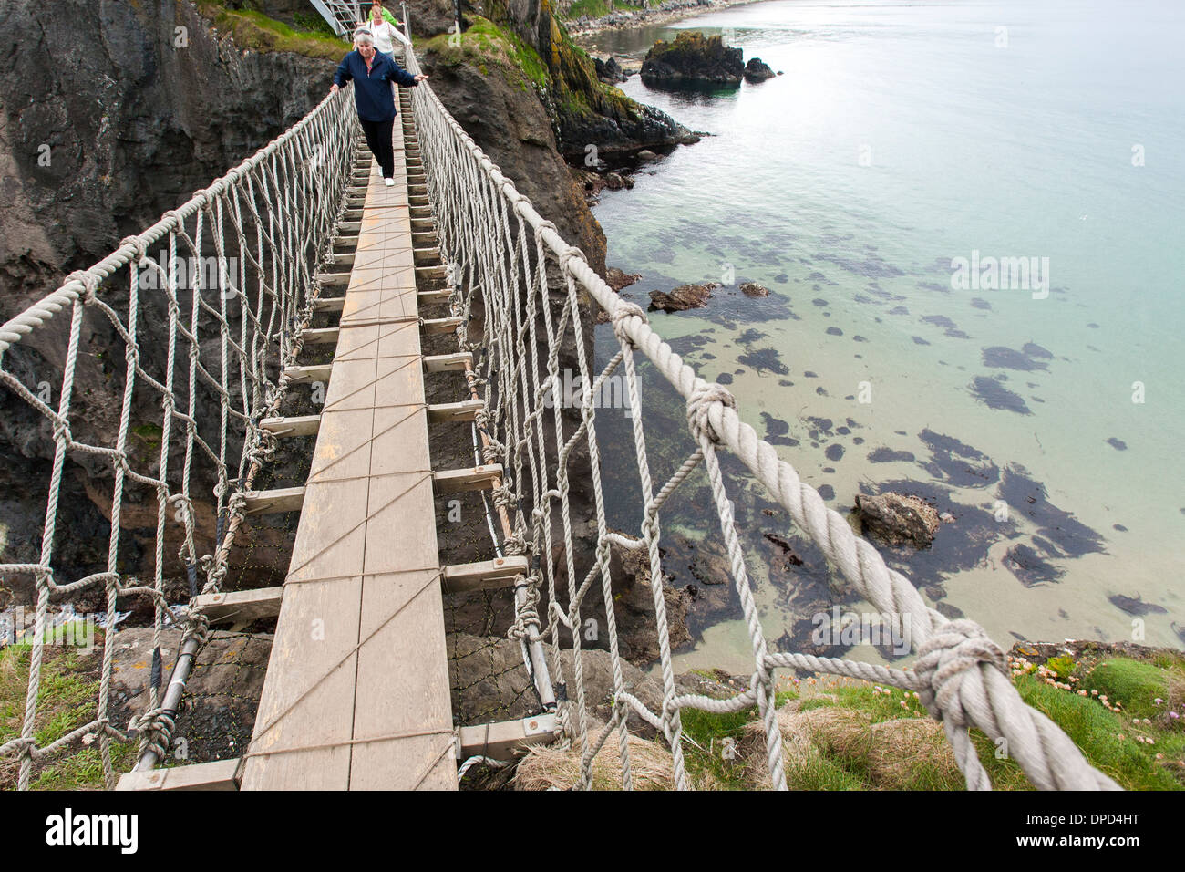 Half way across the Carrick-a-Rede rope bridge on the Antrim coast of ...