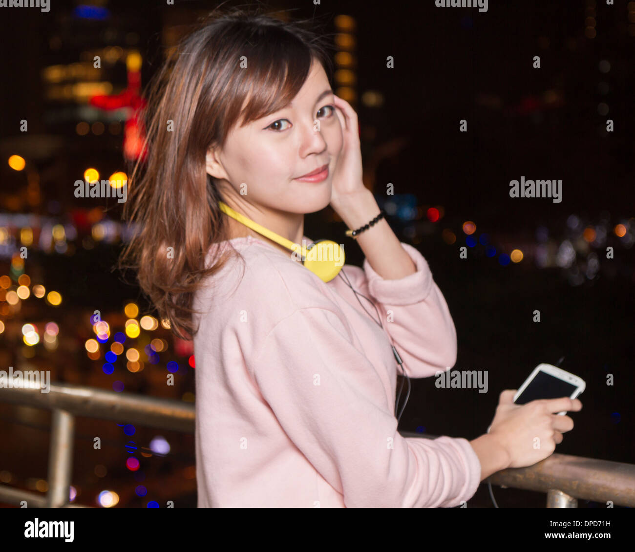 Attractive Malaysian female wearing headphones and holding a cell phone ...