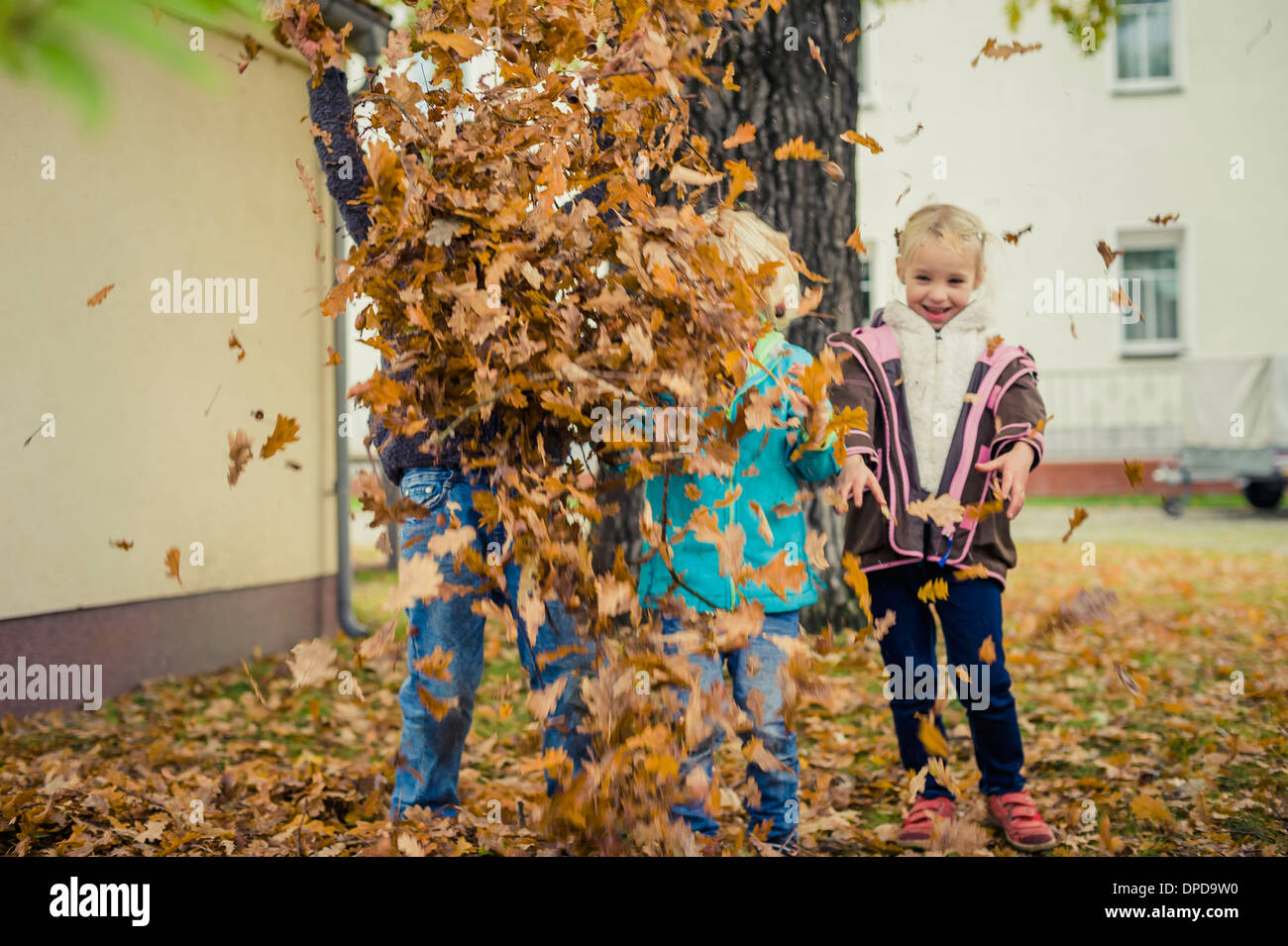 Three children throwing autumn leaves Stock Photo - Alamy