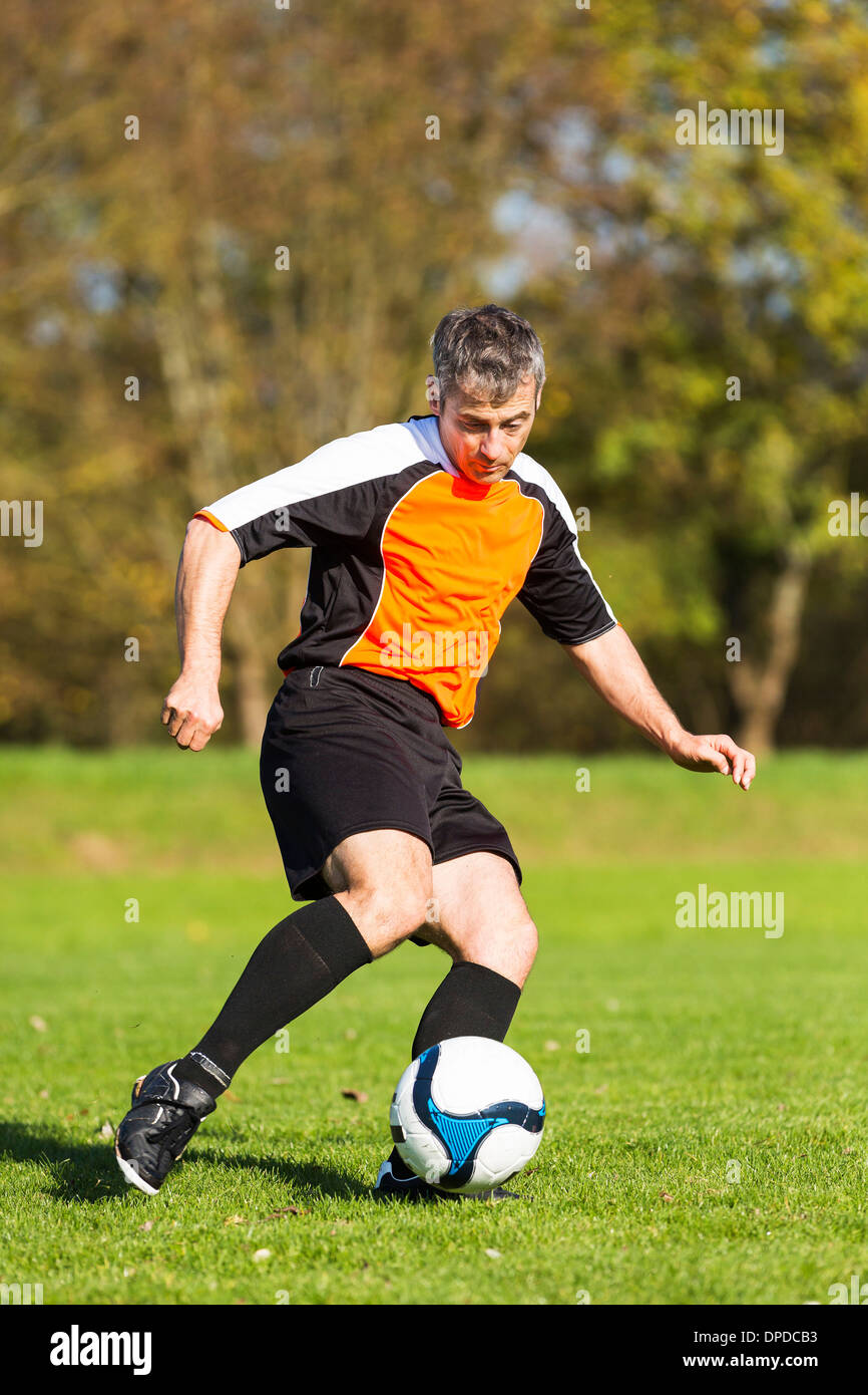 Soccer player with ball on field Stock Photo - Alamy