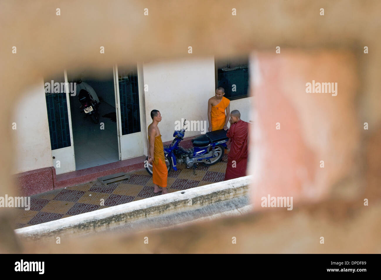 Three Buddhist monks are talking to a motorcycle taxi driver at a ...