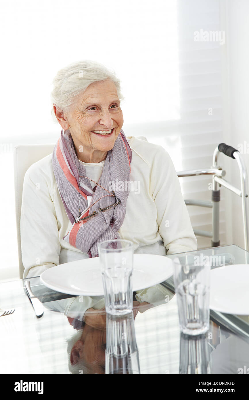 Happy senior woman sitting at set table for lunch Stock Photo - Alamy