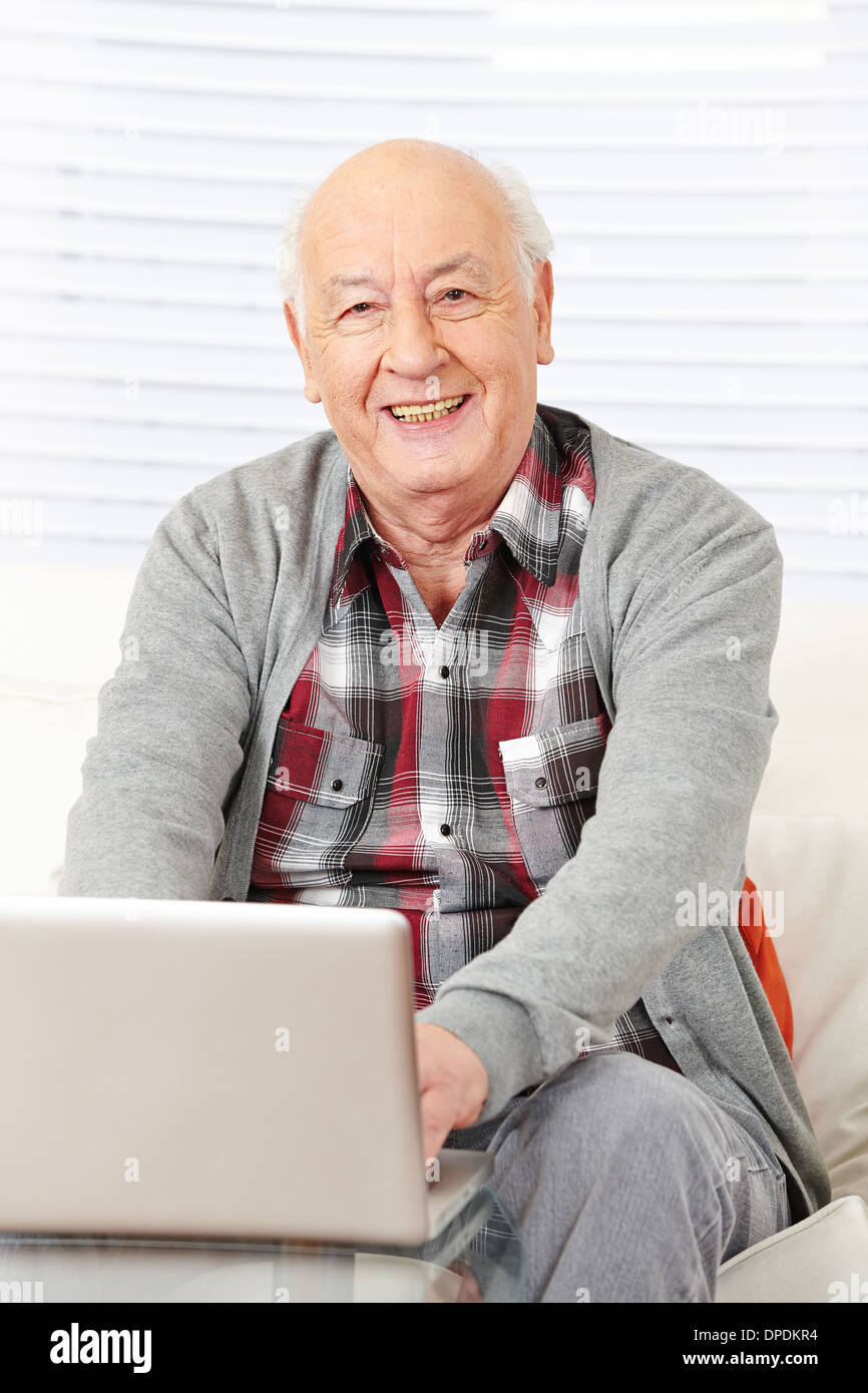 Happy senior citizen man working with laptop computer in the internet ...