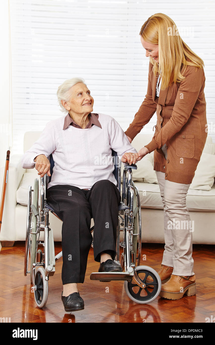 Caregiver helping senior citizen woman in a wheelchair at home Stock ...