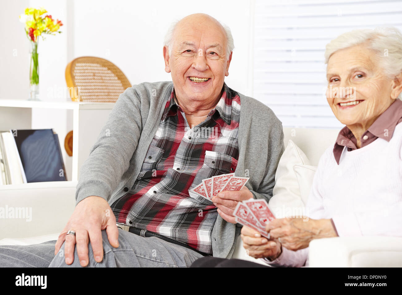 Happy senior citizen couple playing cards at home Stock Photo - Alamy