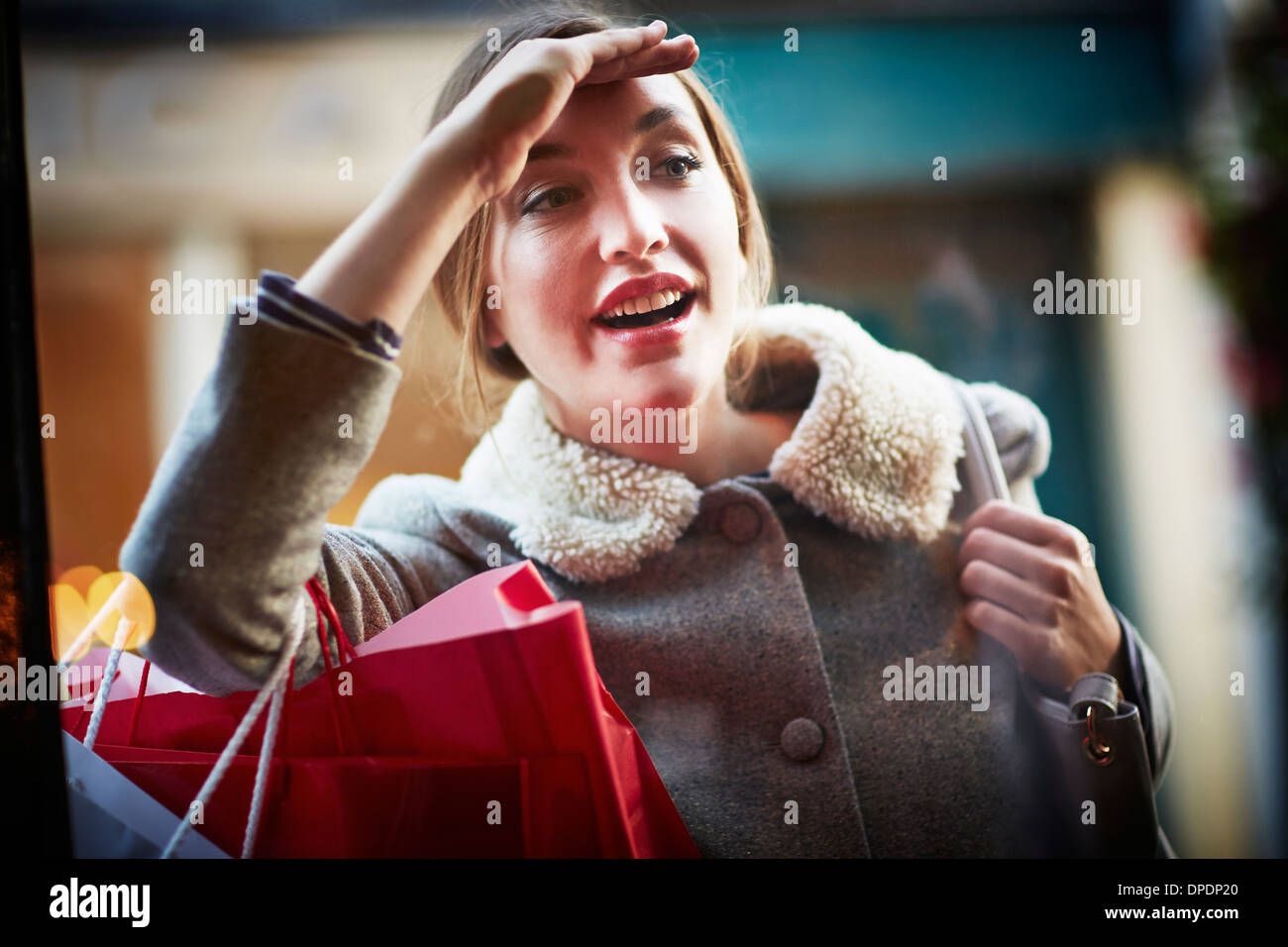 Young woman carrying shopping bag, looking through window Stock Photo ...