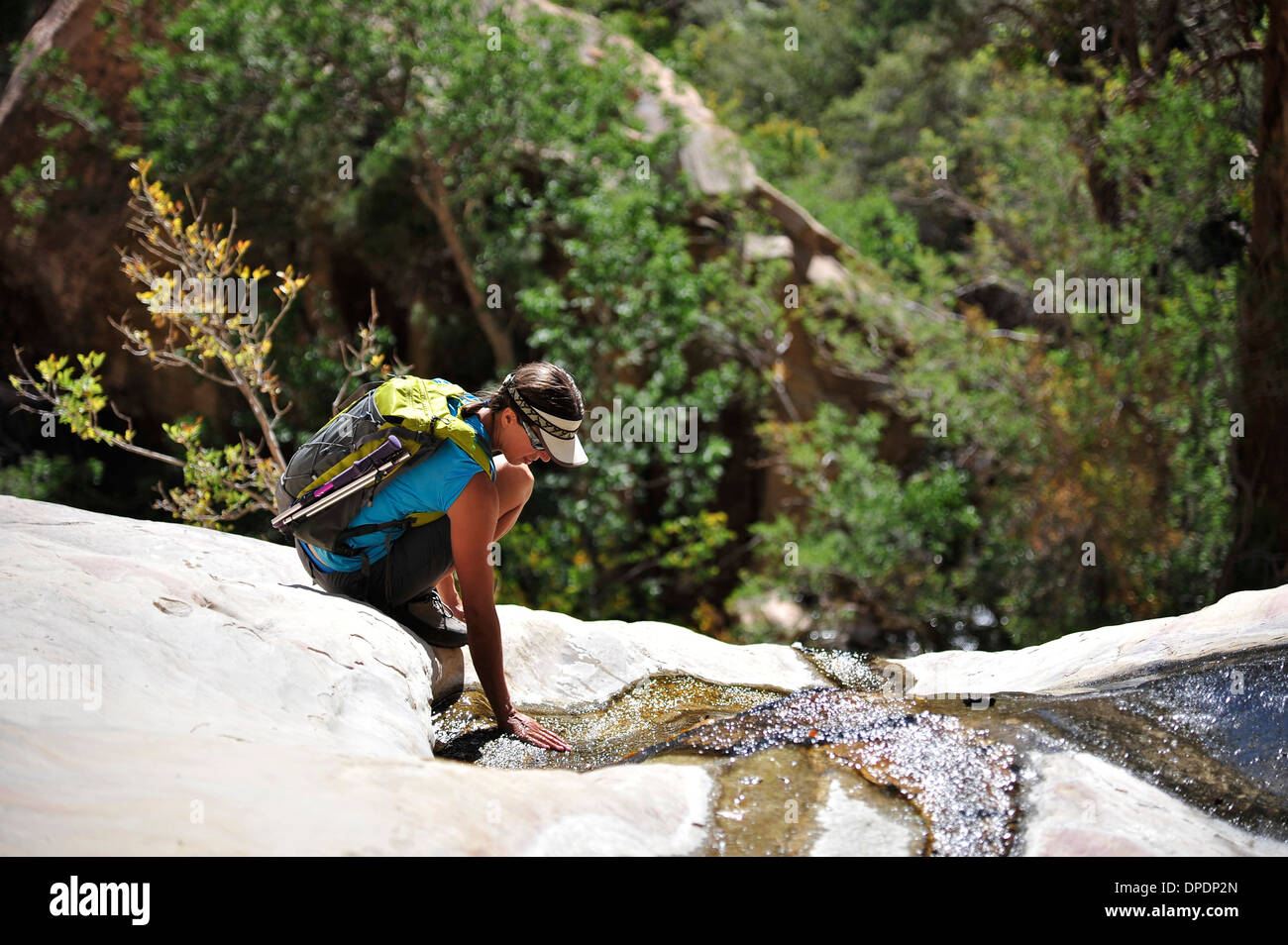 Female hiker crouching on rock, Mount Wilson, Red Rock Canyon, Nevada ...