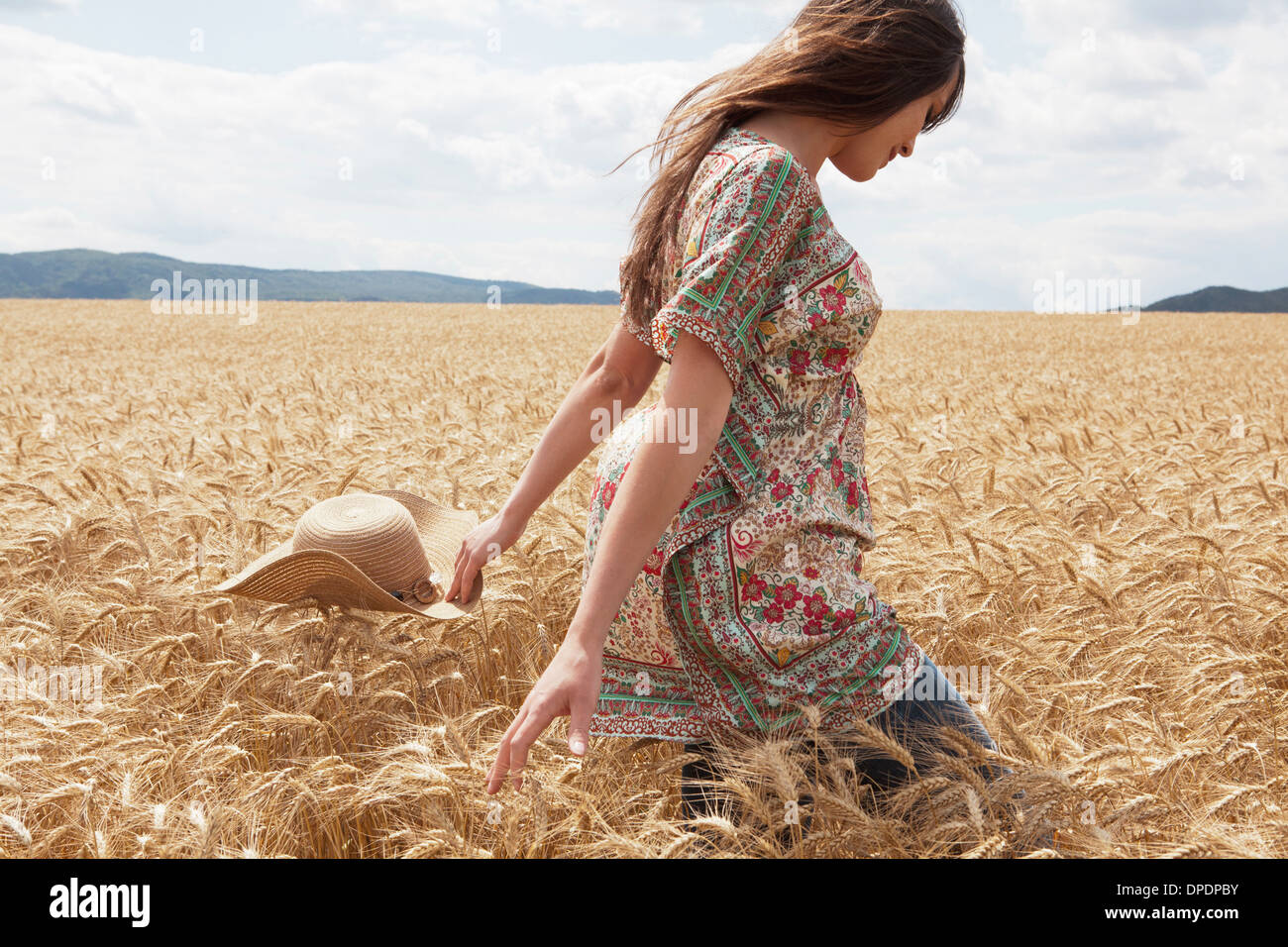 Mid adult woman walking through wheat field Stock Photo - Alamy