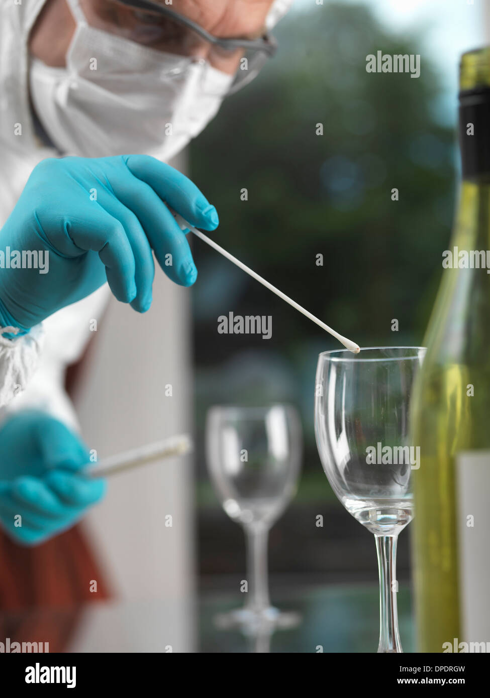 Forensic scientist using a DNA swab to take evidence from a glass at a ...