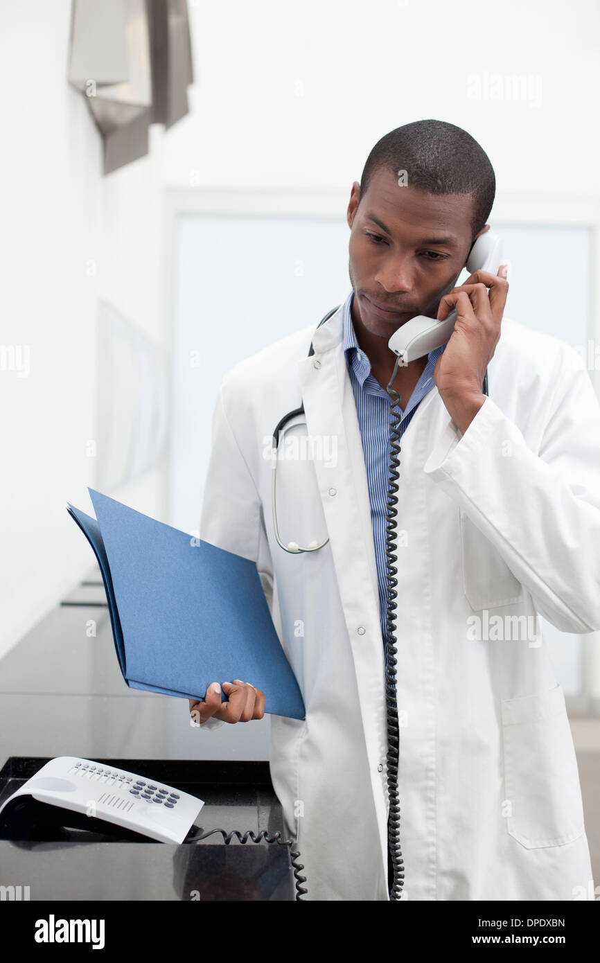 Doctor on telephone call, holding paperwork Stock Photo - Alamy