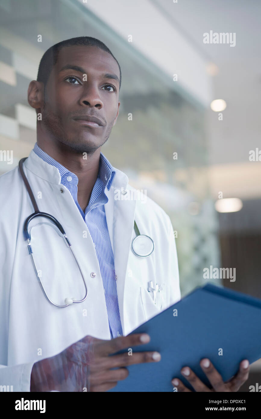 Doctor standing in hospital corridor holding paperwork Stock Photo - Alamy