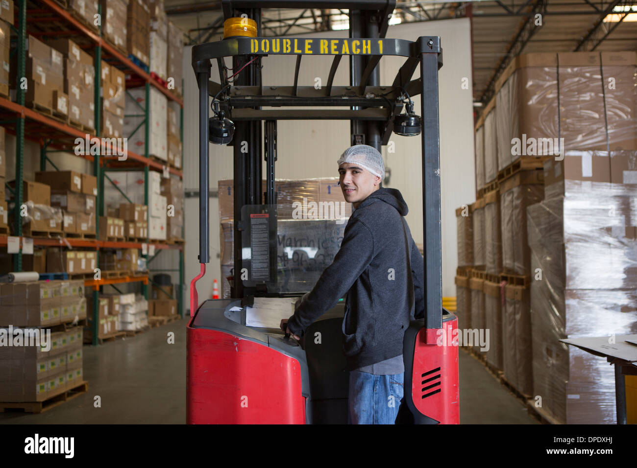 Factory worker with fork lift in warehouse Stock Photo - Alamy