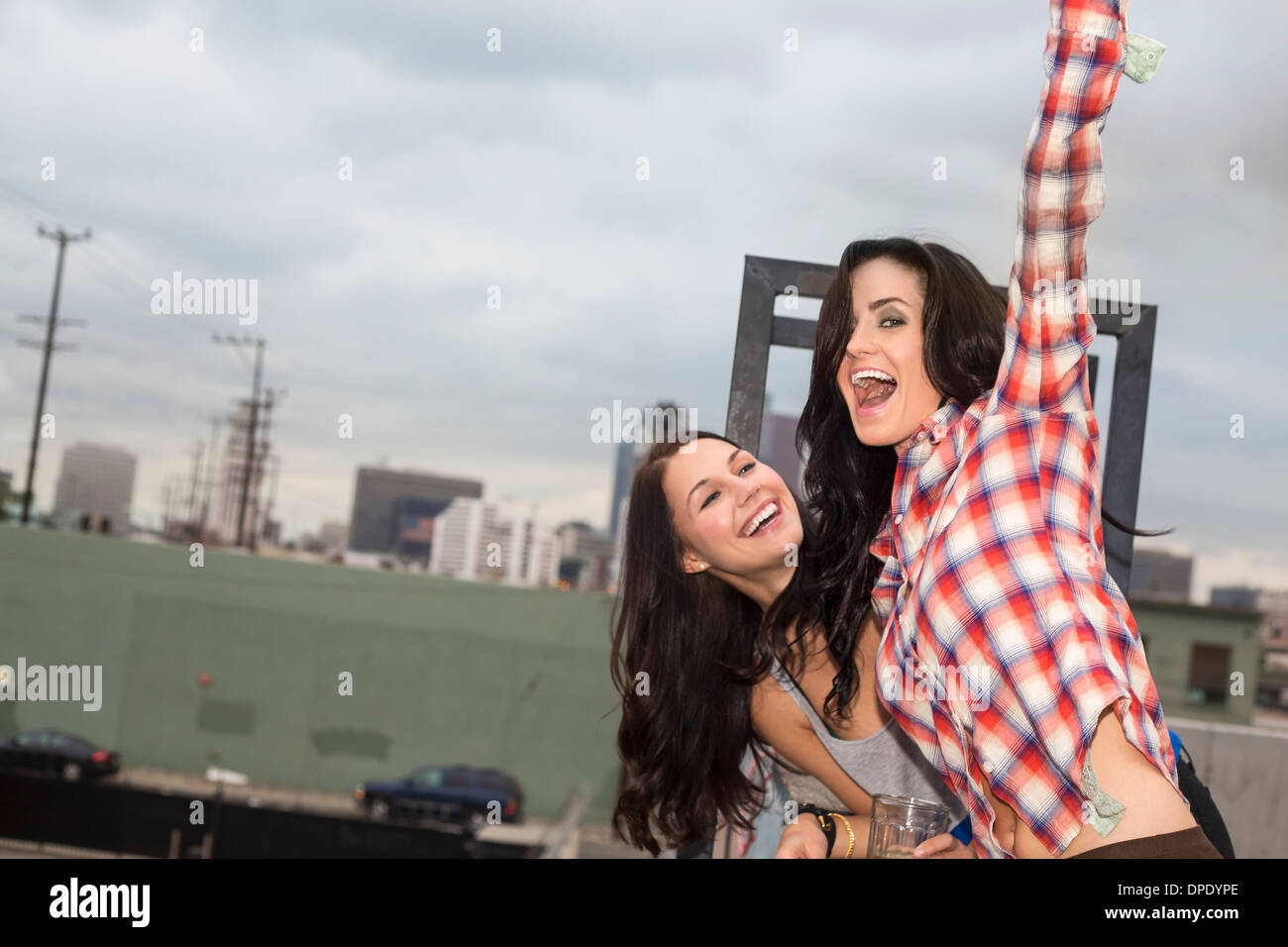 Two female friends jumping around at rooftop party Stock Photo - Alamy