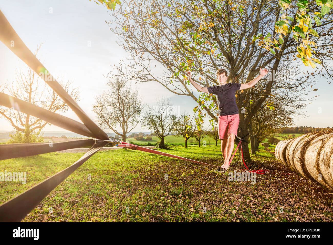Portrait of young man walking on slackline Stock Photo - Alamy