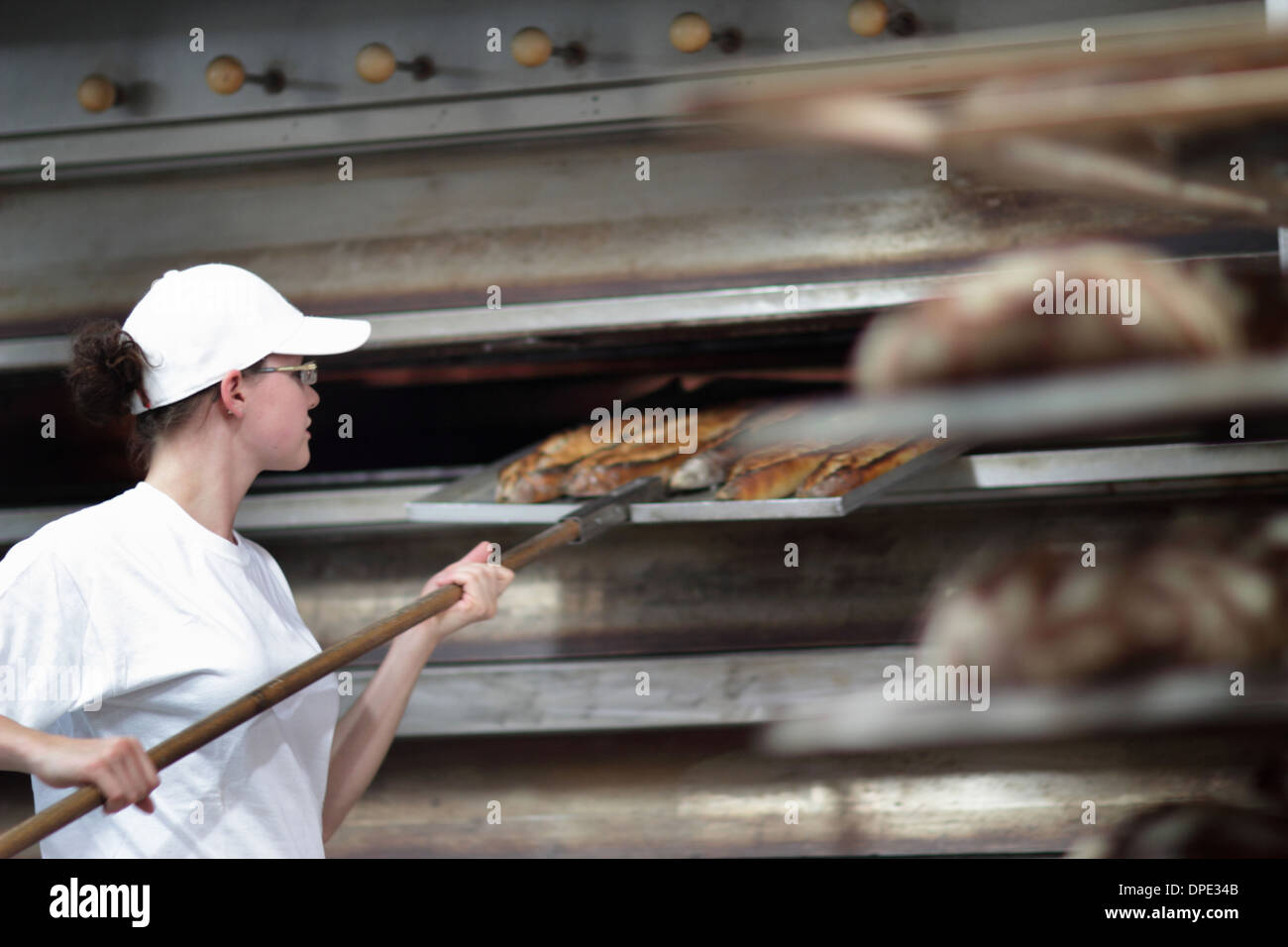 Baker putting bread on shelf Stock Photo - Alamy