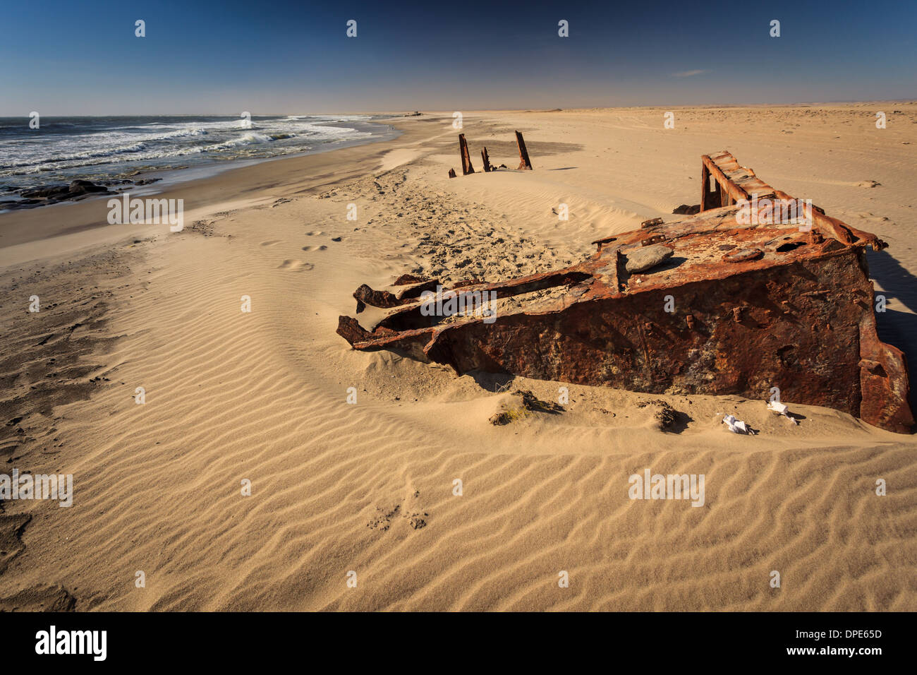 Close up view of rusted hull of a cargo ship buried in the sand on ...