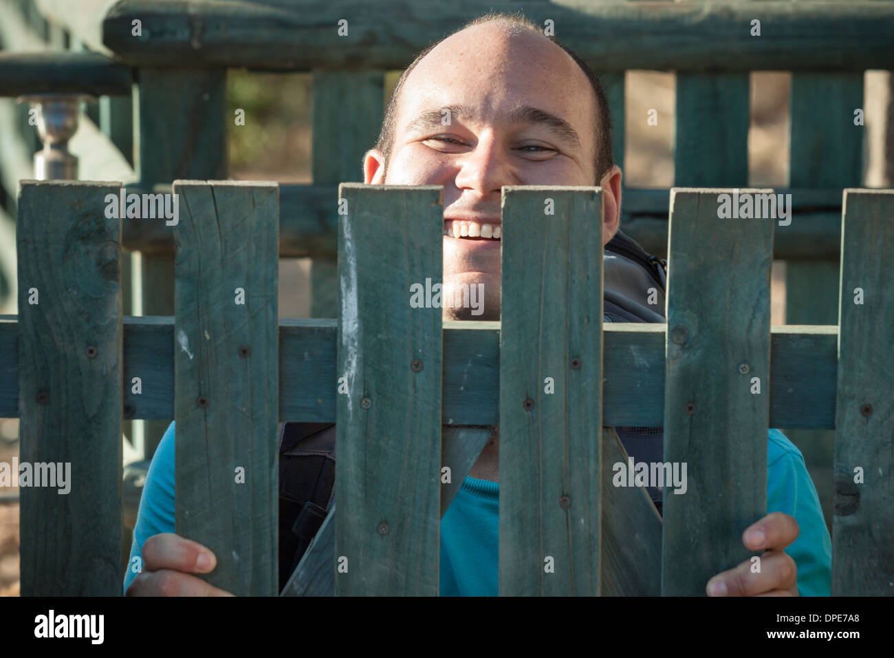 Funny man smiling behind wooden fence Stock Photo - Alamy