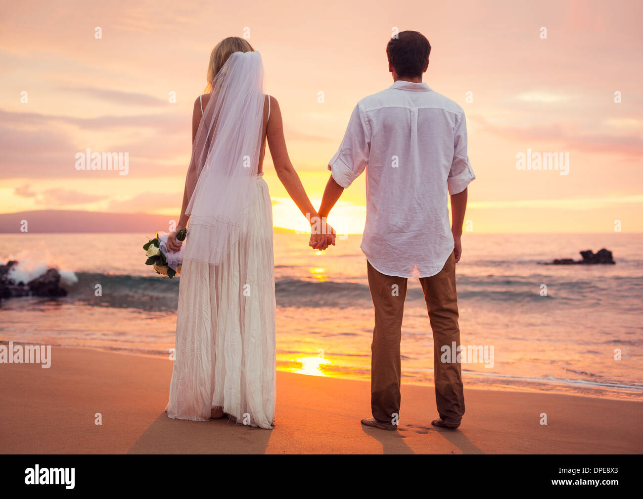 Married couple, bride and groom at sunset on beautiful tropical beach ...
