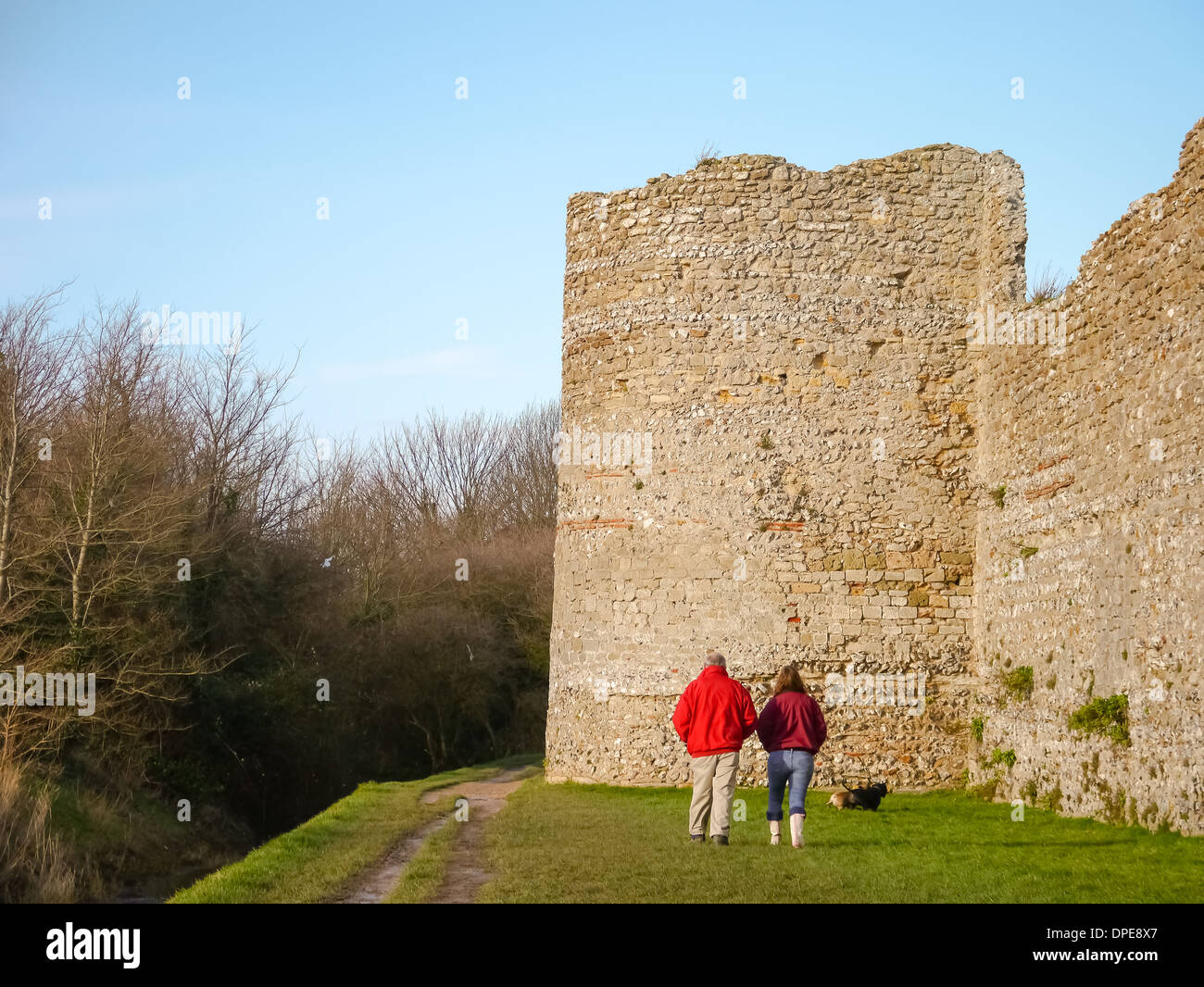 An adult couple walking their dog around the perimeter wall of ...