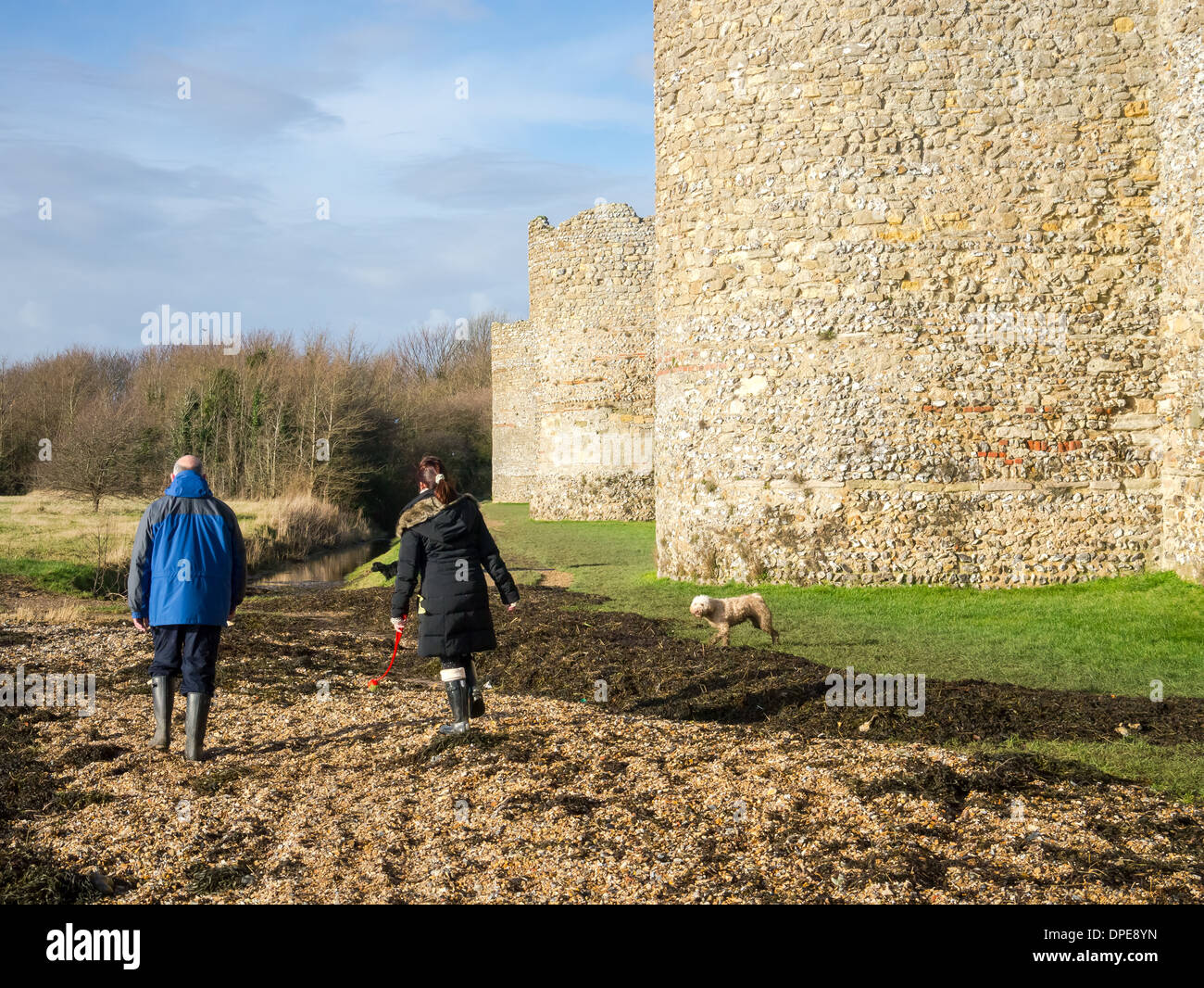 An adult couple walking their dog around the perimeter wall of ...