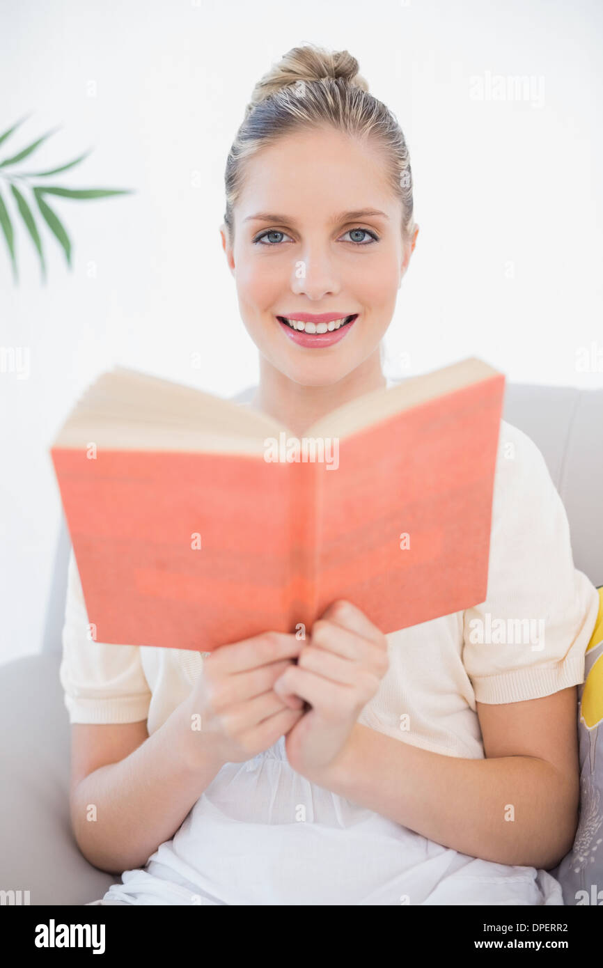 Smiling fresh model reading book sitting on sofa Stock Photo - Alamy
