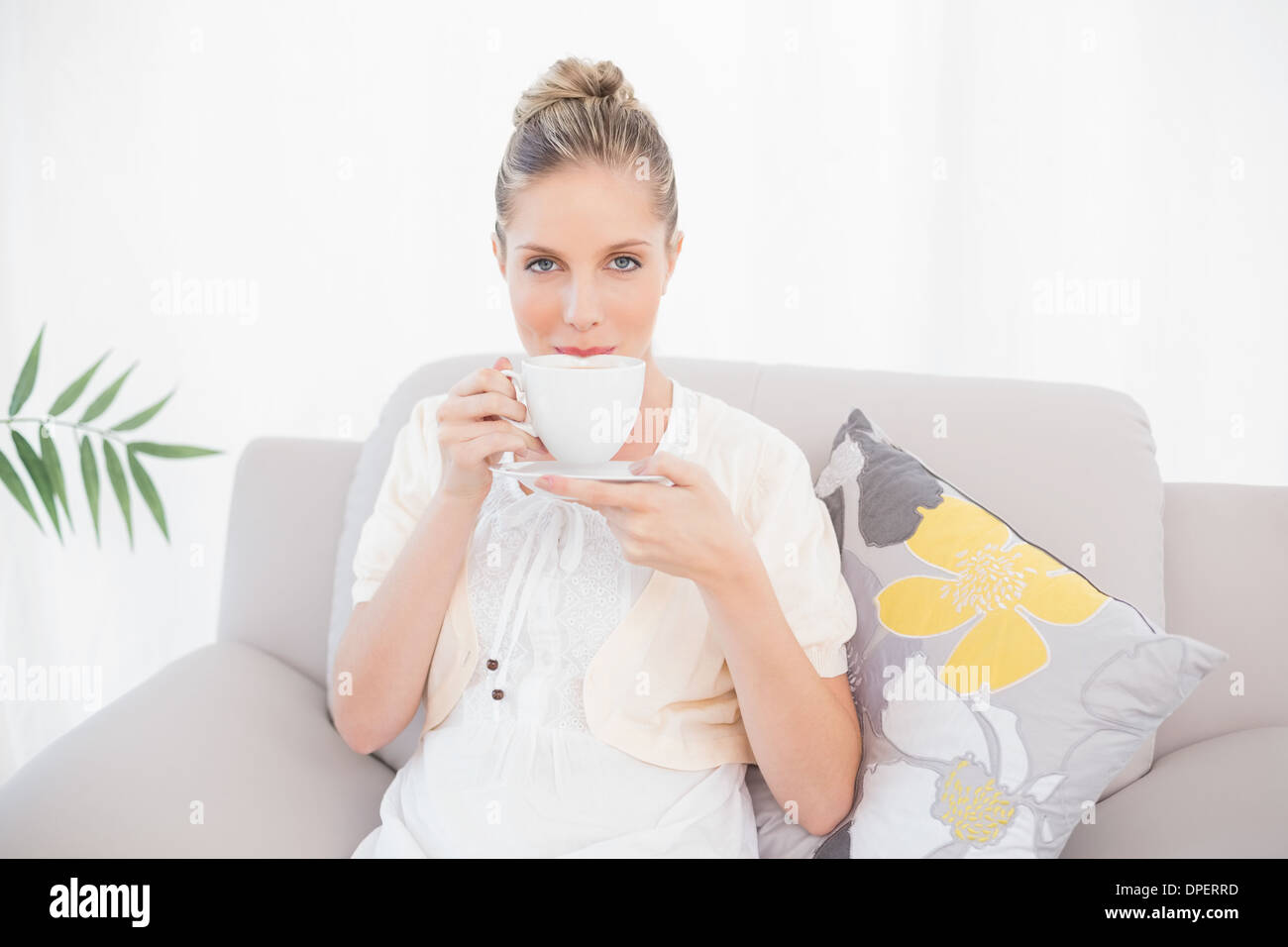 Charming fresh model drinking coffee sitting on sofa Stock Photo - Alamy