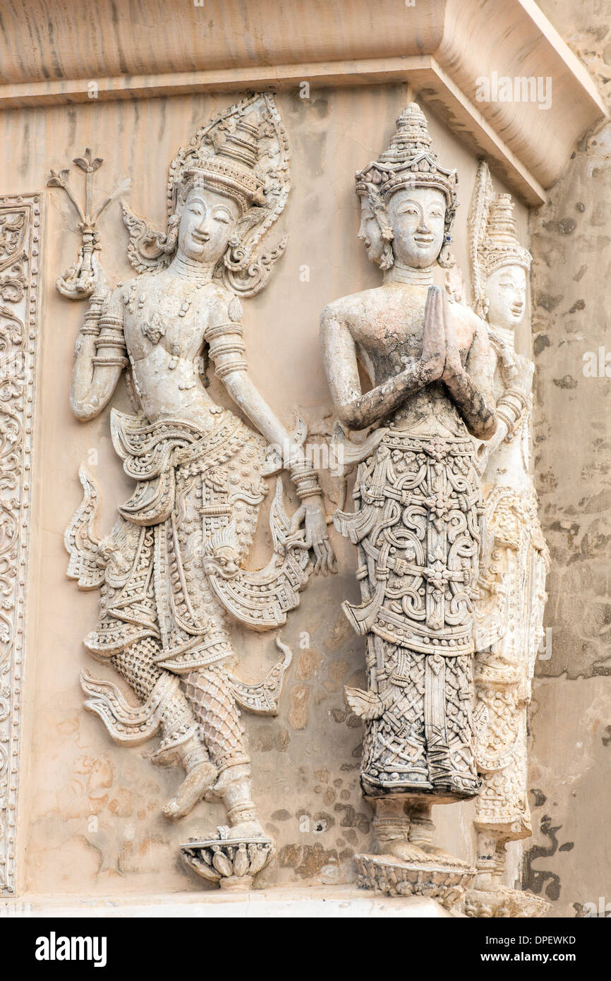 Stone praying women carvings on the wall of the temple in Thailand ...