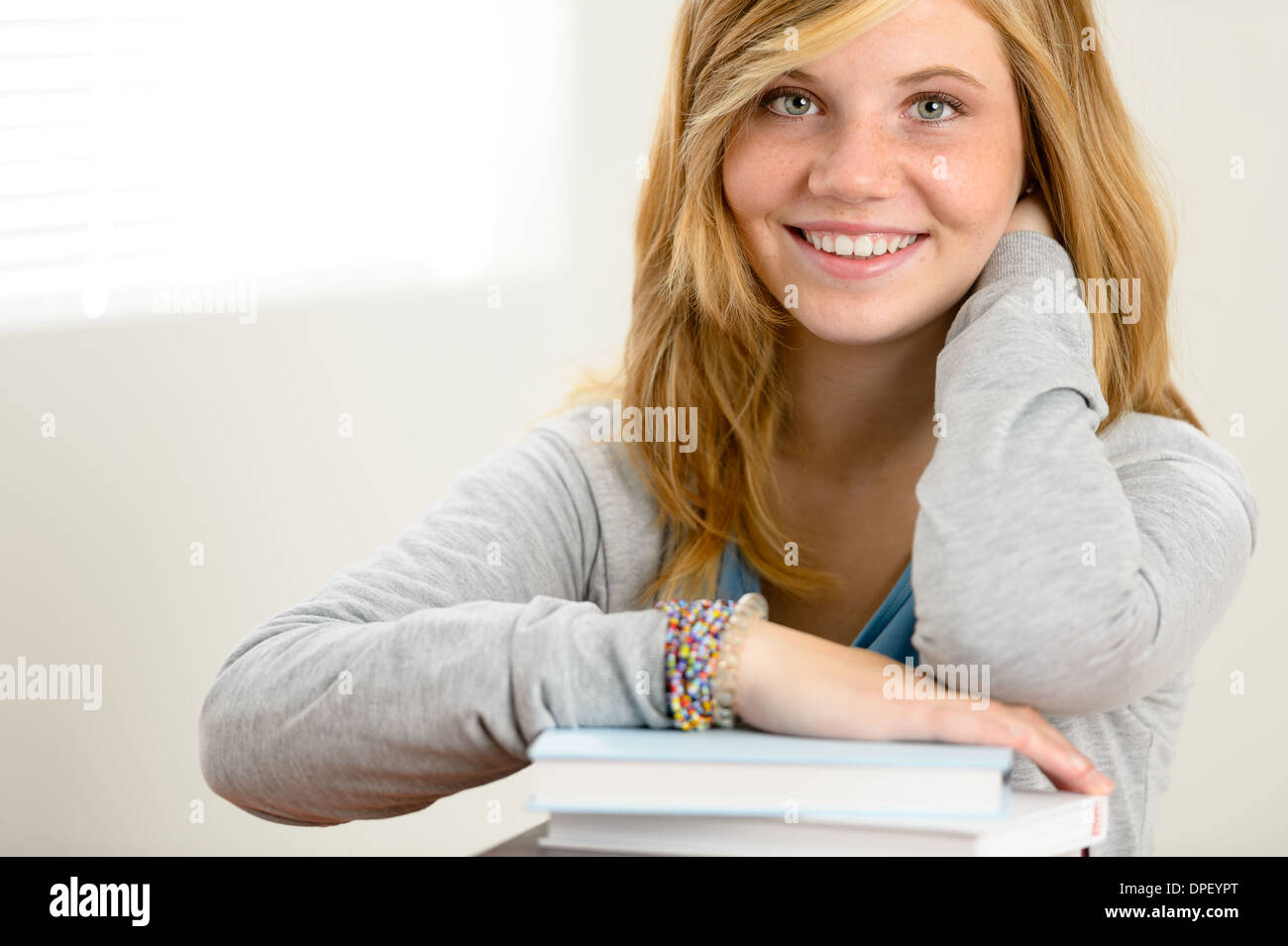 Happy student girl leaning over pile of books Stock Photo - Alamy