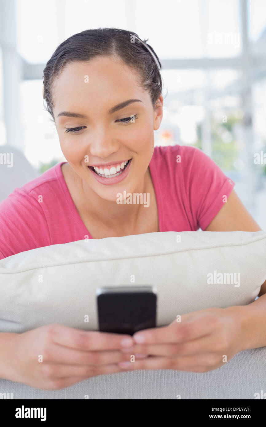 Smiling woman lying on sofa and texting Stock Photo - Alamy