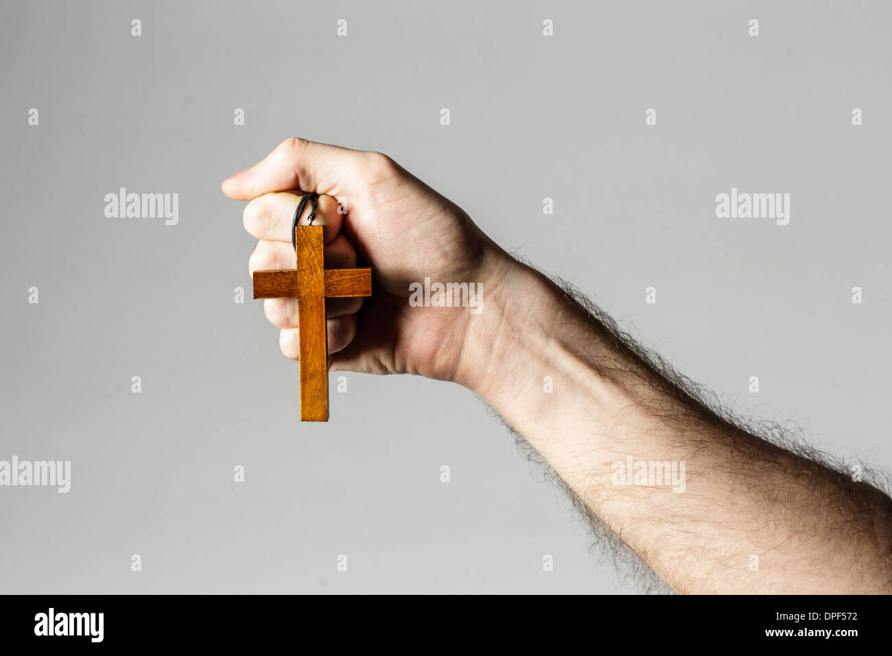 Male hand holding wooden cross on gray background Stock Photo - Alamy