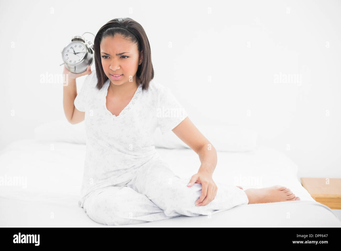 Angry young dark haired model throwing an alarm clock Stock Photo - Alamy