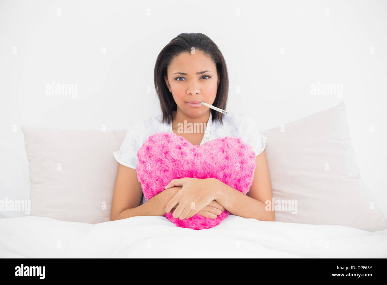 Anxious young dark haired model using a thermometer Stock Photo - Alamy