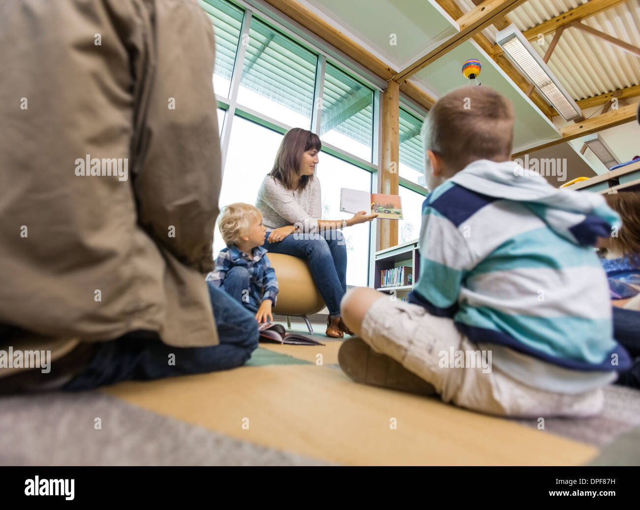 Teacher Reading To Students In Library Stock Photo - Alamy