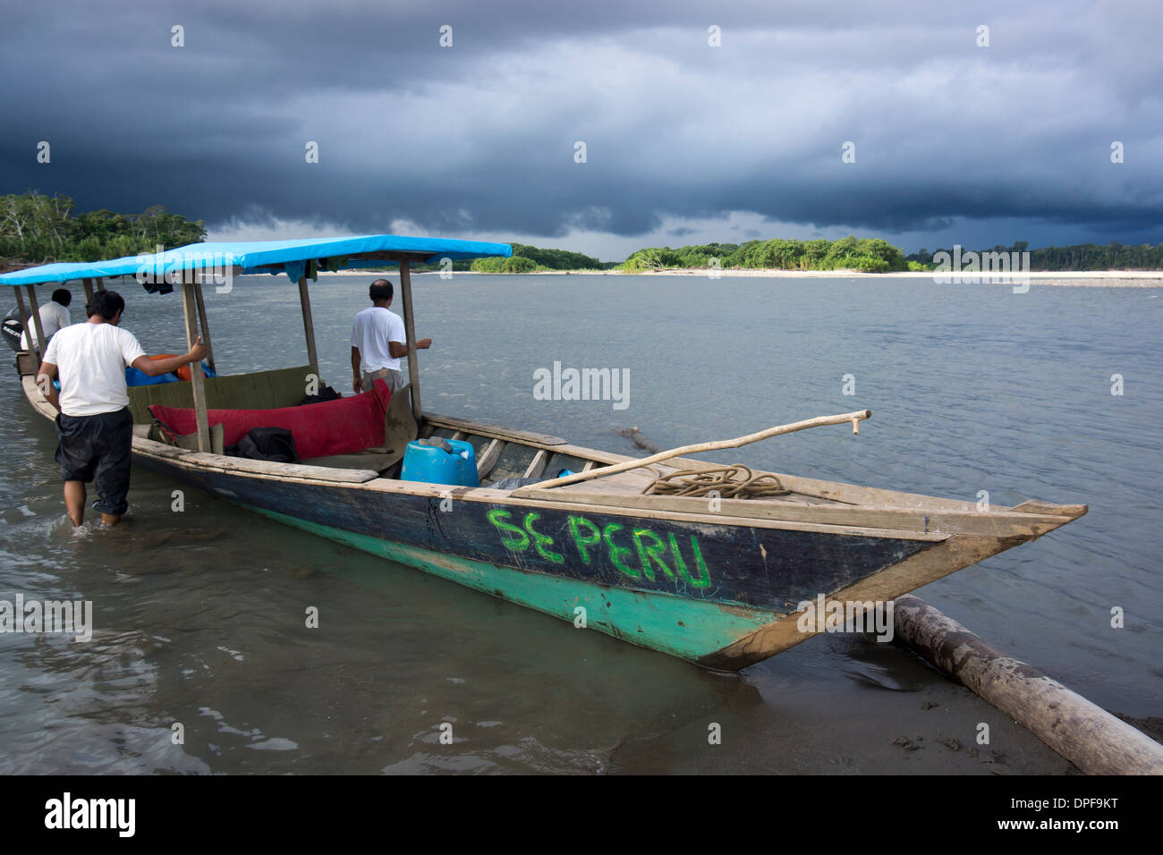 Dark clouds and tourist boat on the Manu river, Manu National Park ...