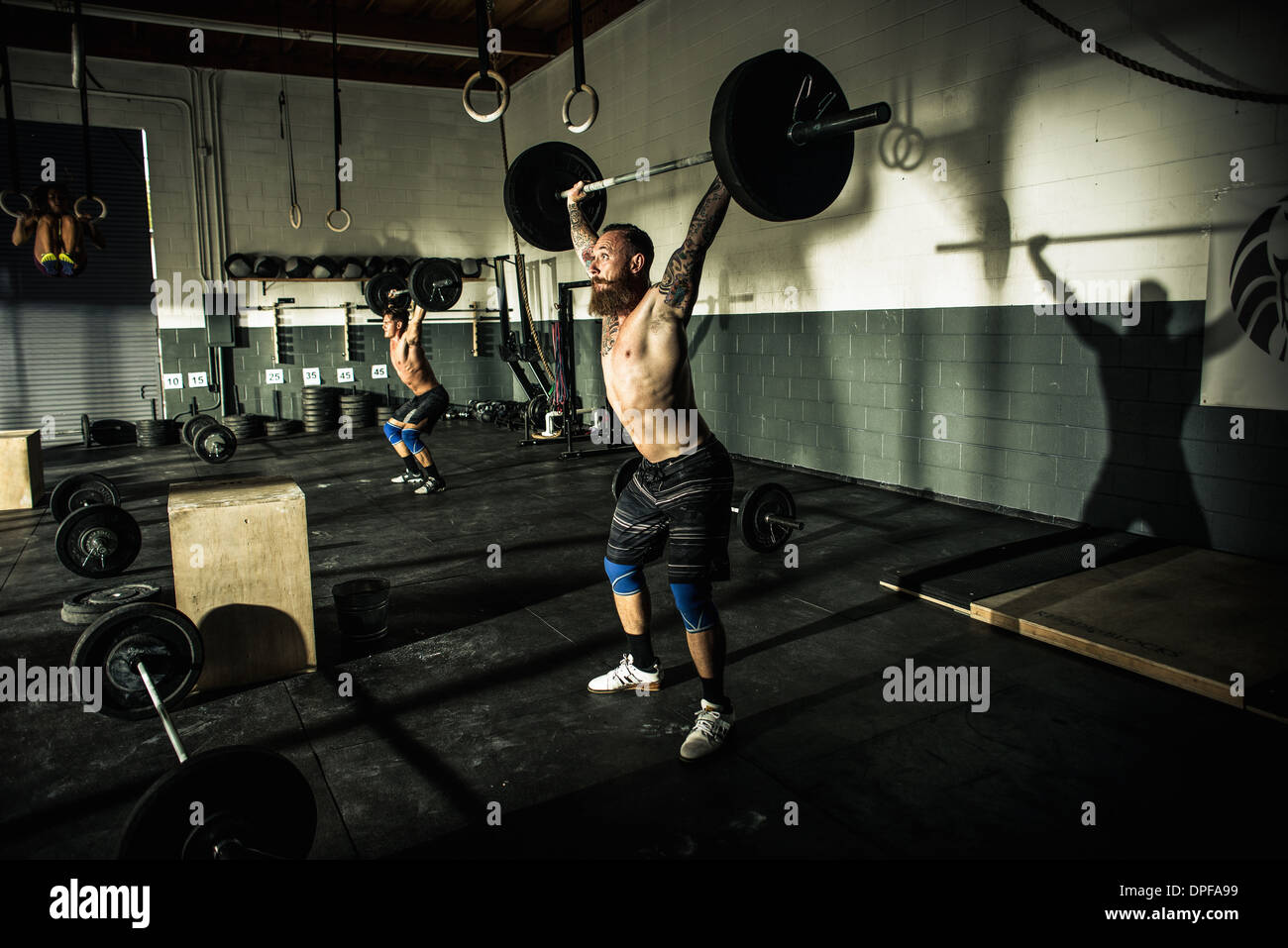 Two men lifting barbels in gymnasium Stock Photo - Alamy
