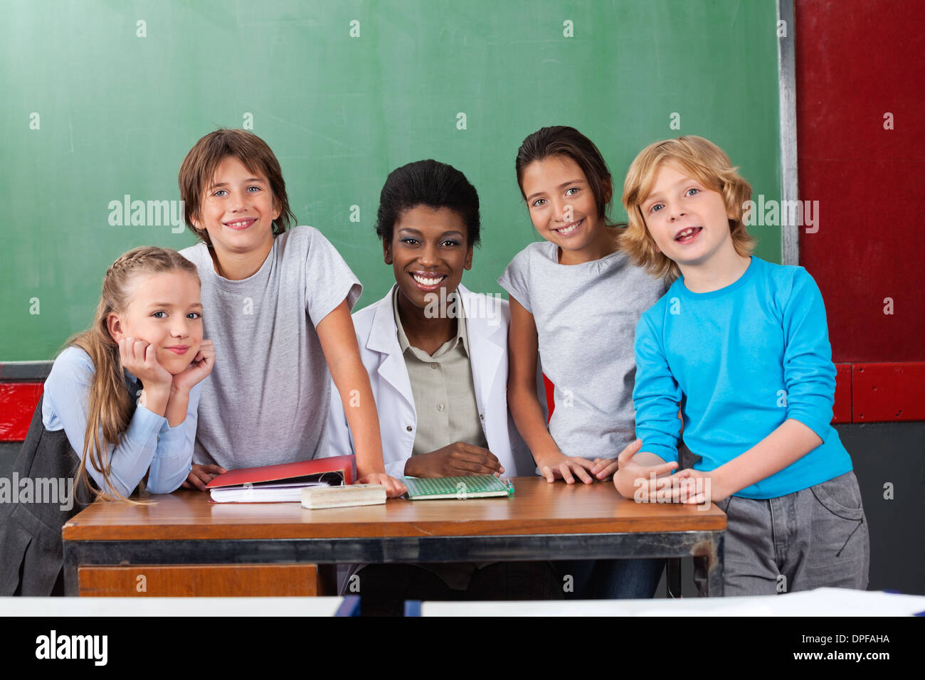 Happy Teacher With Students At Desk Stock Photo - Alamy