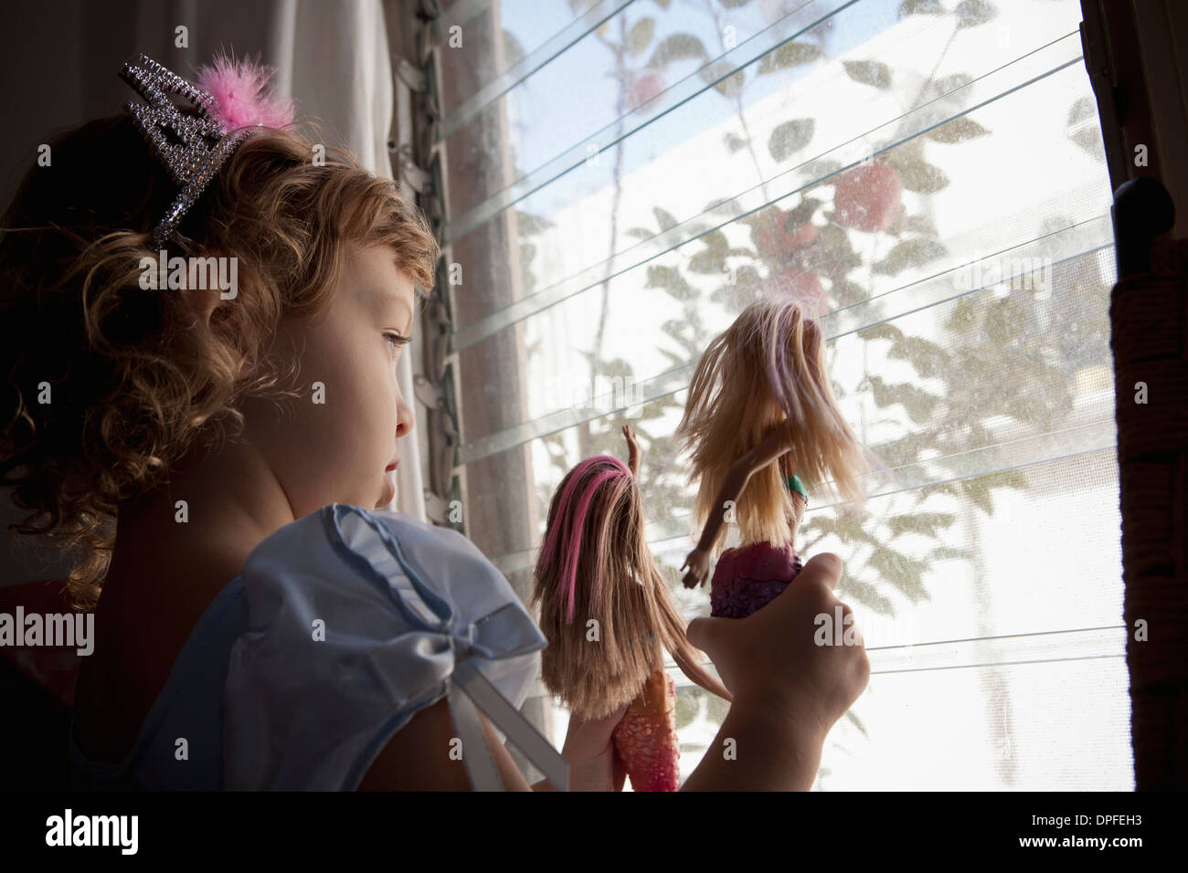 Female toddler looking out of window holding up dolls Stock Photo - Alamy