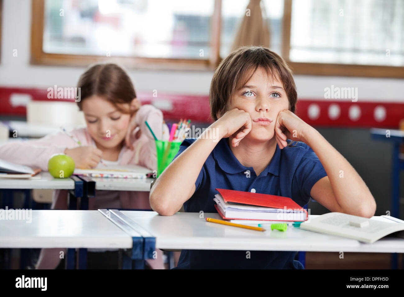 Bored Schoolboy Looking Away Sitting At Desk In Classroom Stock Photo ...