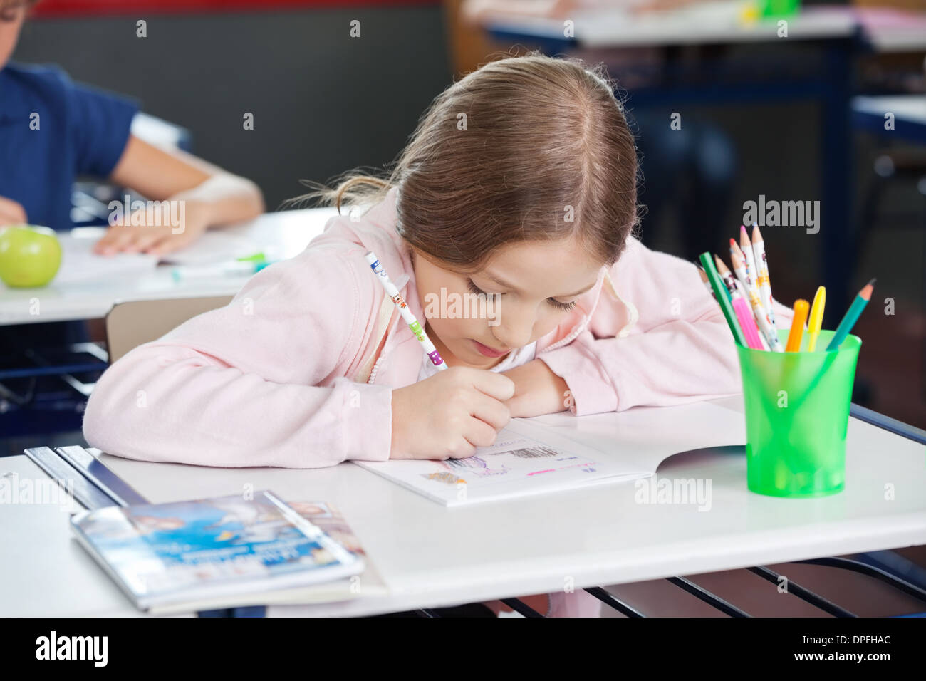 Schoolgirl Drawing In Book At Desk Stock Photo - Alamy