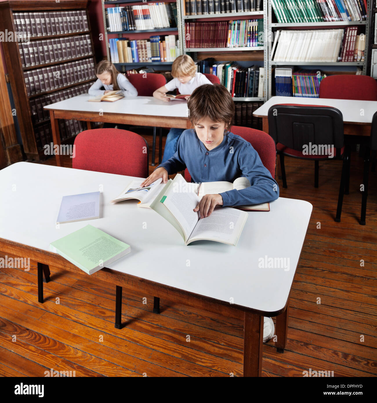 Little Boy Reading Books In Library Stock Photo - Alamy