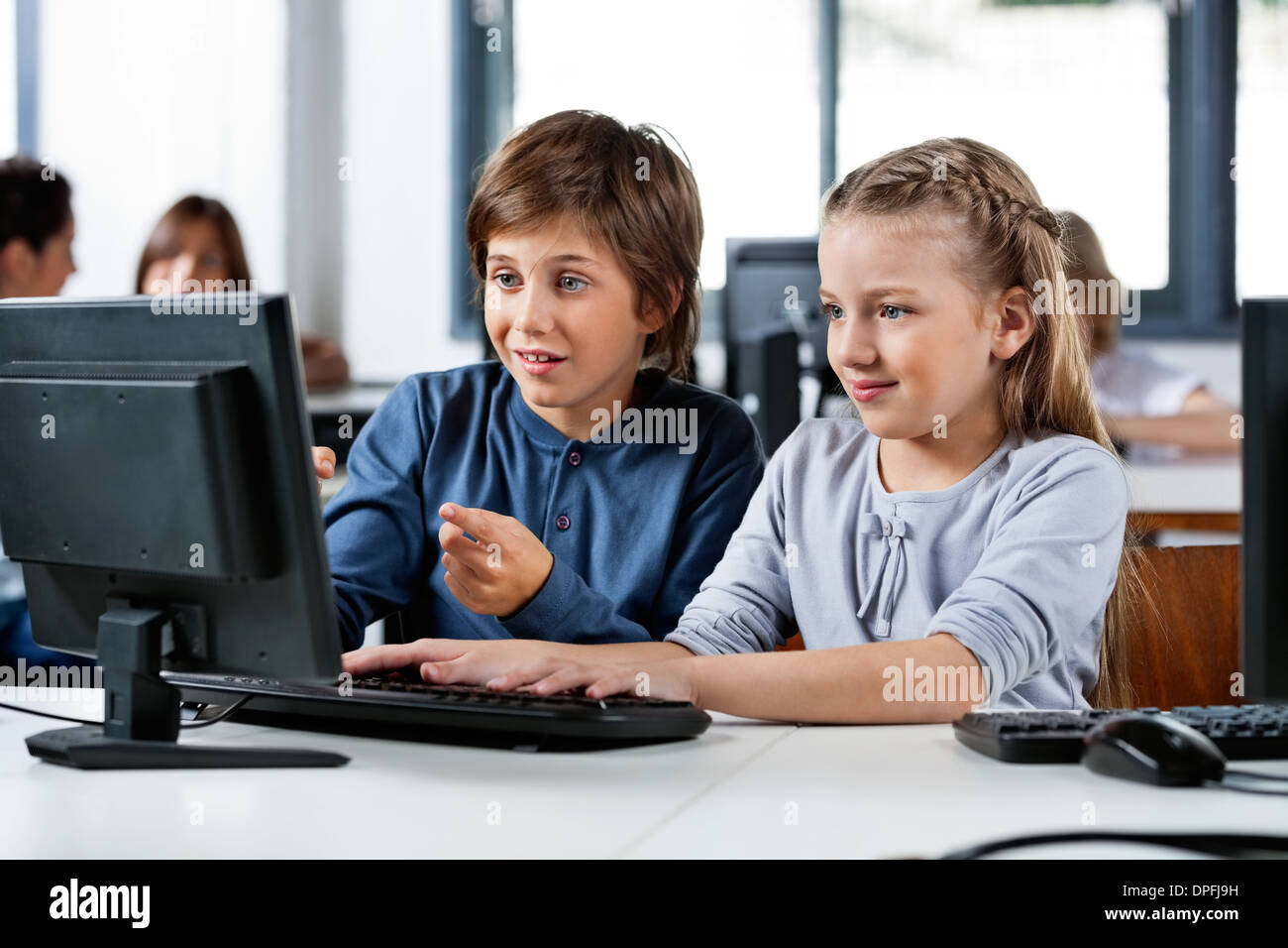 Boy Pointing While Using Desktop Pc With Friend At Desk Stock Photo - Alamy