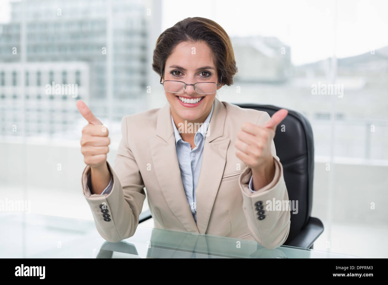 Happy businesswoman showing thumbs up at her desk Stock Photo - Alamy