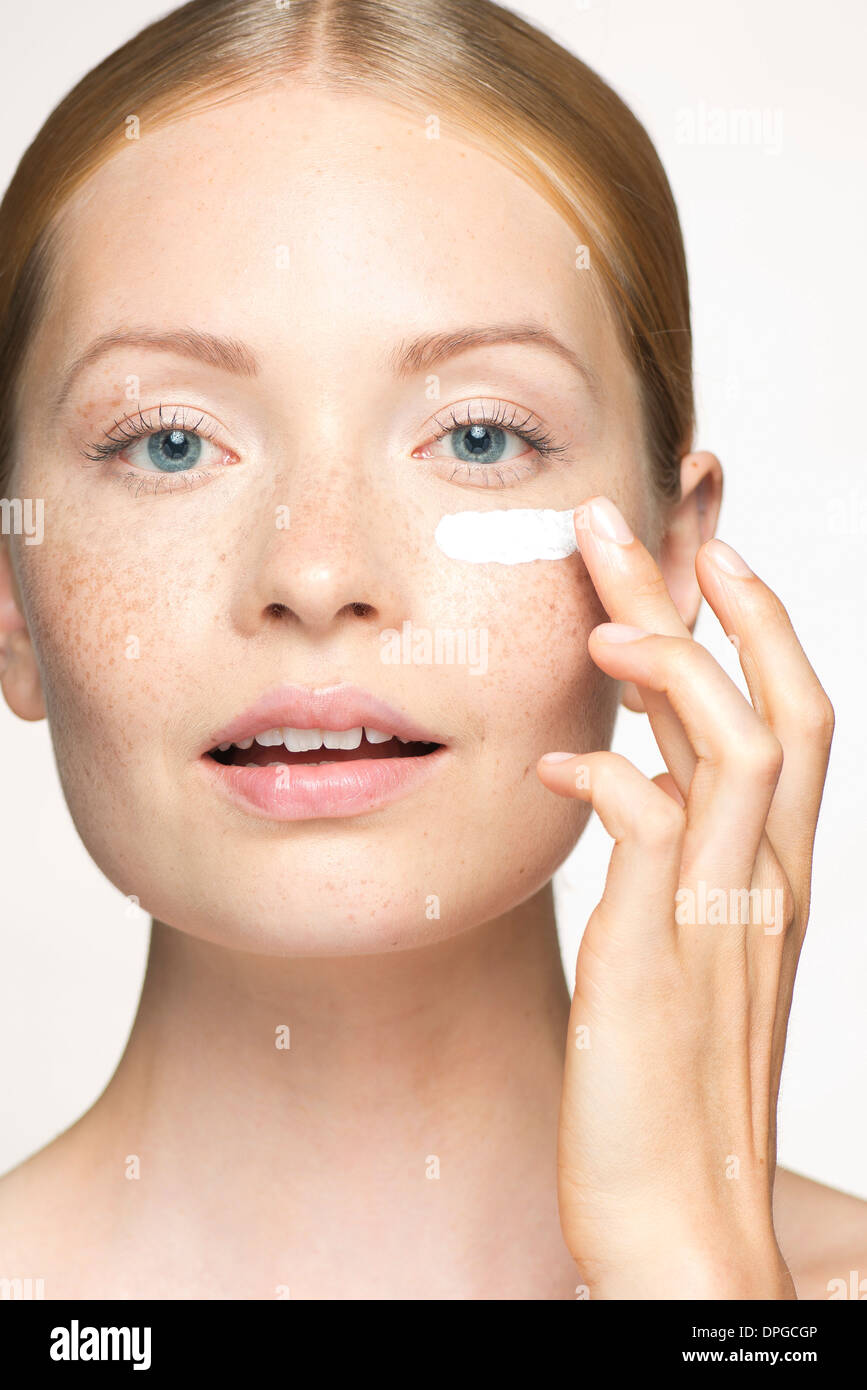 Young woman applying moisturizer under eye Stock Photo - Alamy