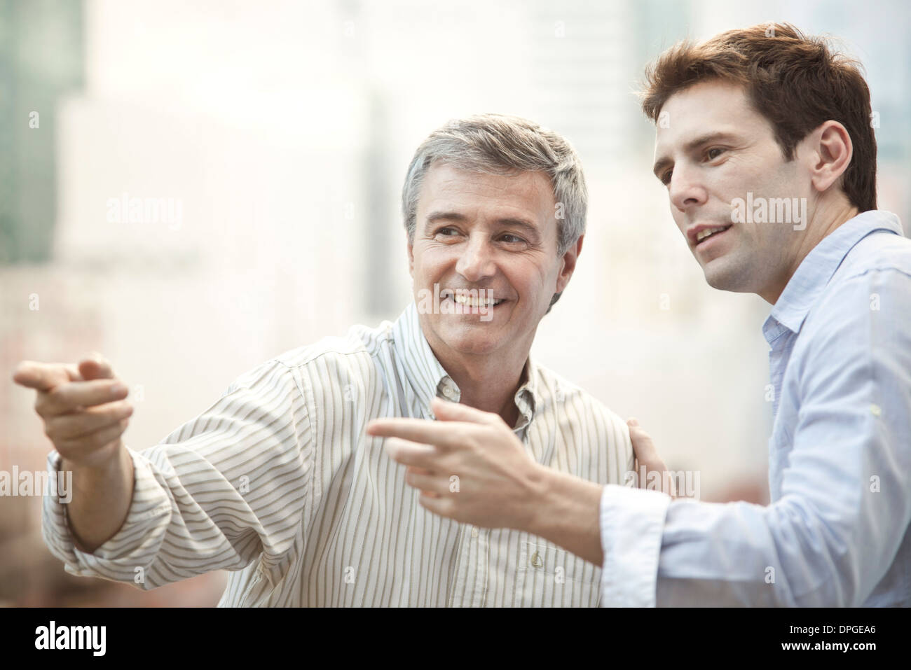 Friends hanging out, pointing into distance Stock Photo - Alamy