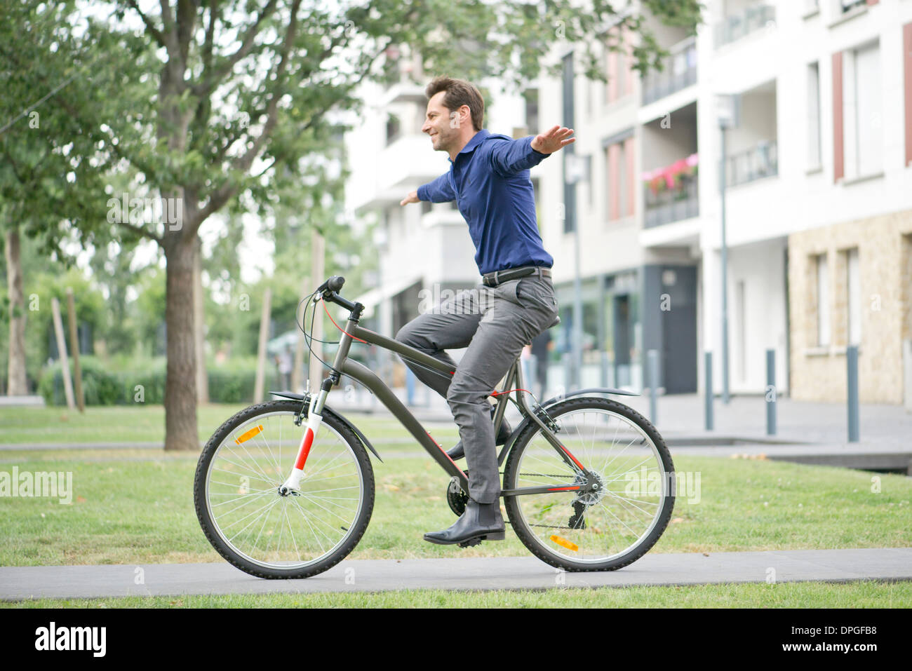 Man riding bicycle with arms outstretched Stock Photo - Alamy