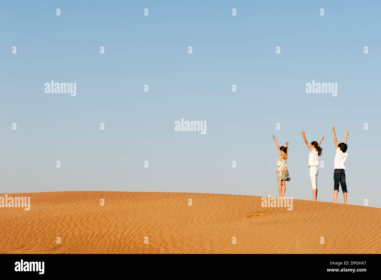 Children standing in desert with arms raised in air Stock Photo - Alamy
