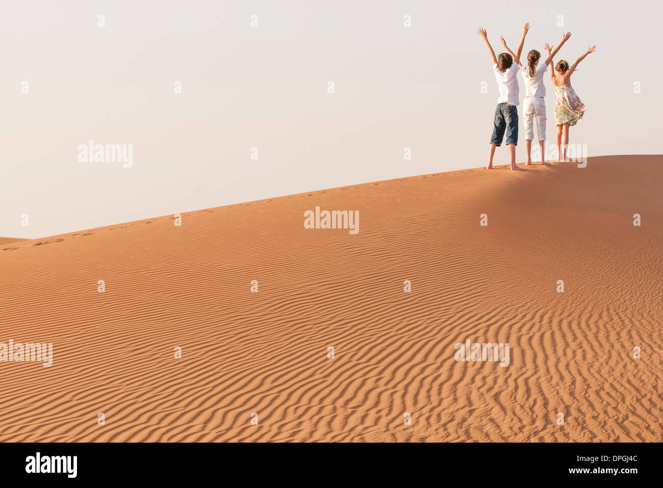Children standing in desert with arms raised in air Stock Photo - Alamy