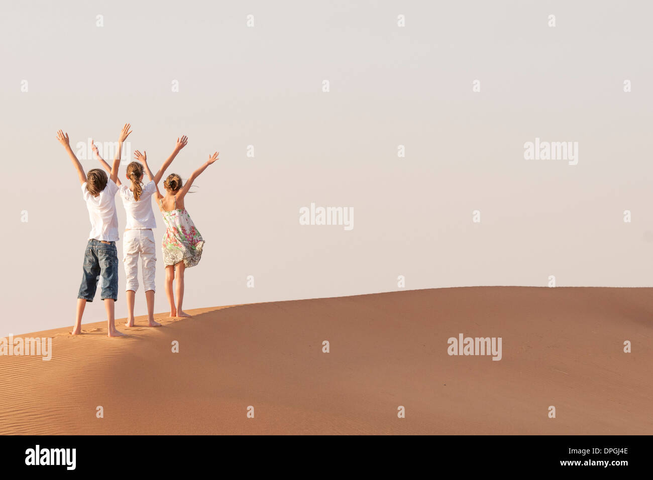 Children standing in desert with arms raised in air Stock Photo - Alamy